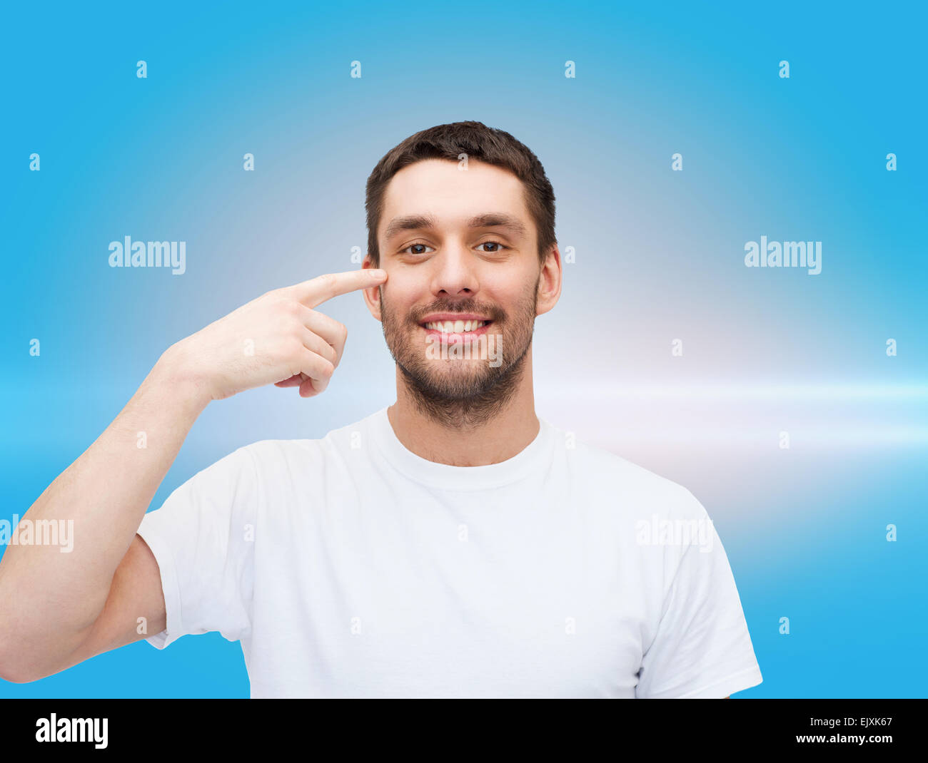 smiling young handsome man pointing to eyes Stock Photo - Alamy