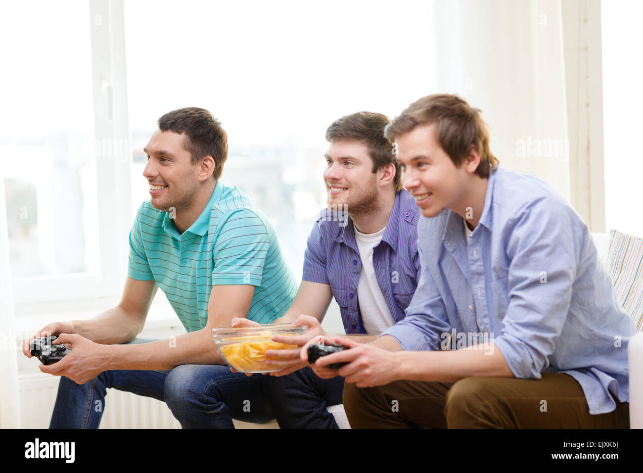smiling friends playing video games at home Stock Photo - Alamy