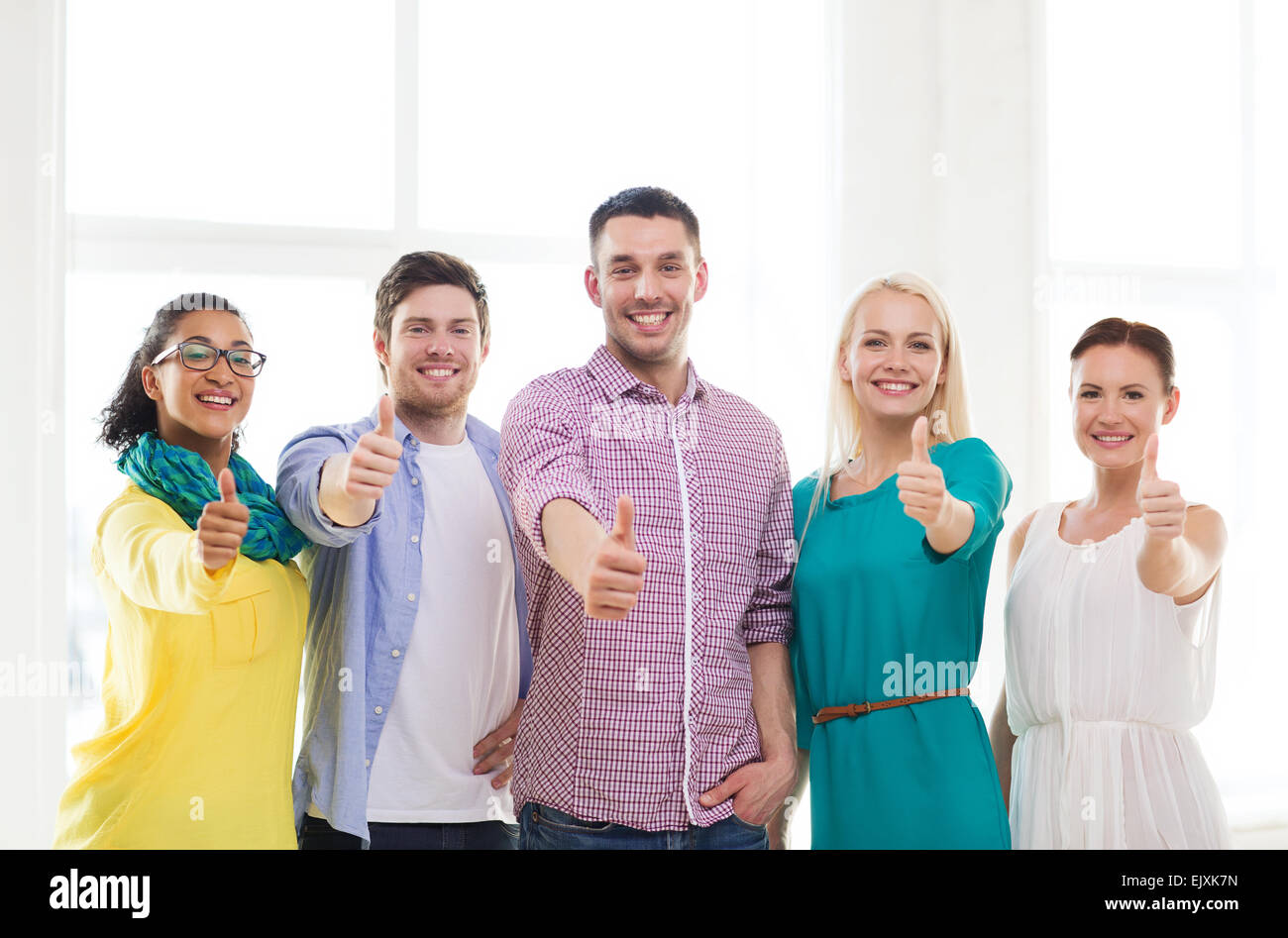 happy creative team showing thumbs up in office Stock Photo - Alamy