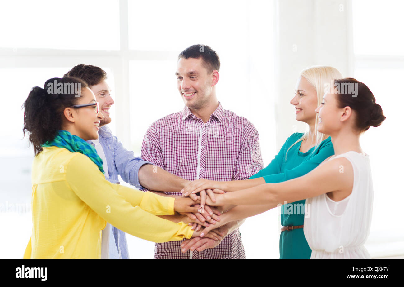 team with hands on top of each other in office Stock Photo - Alamy