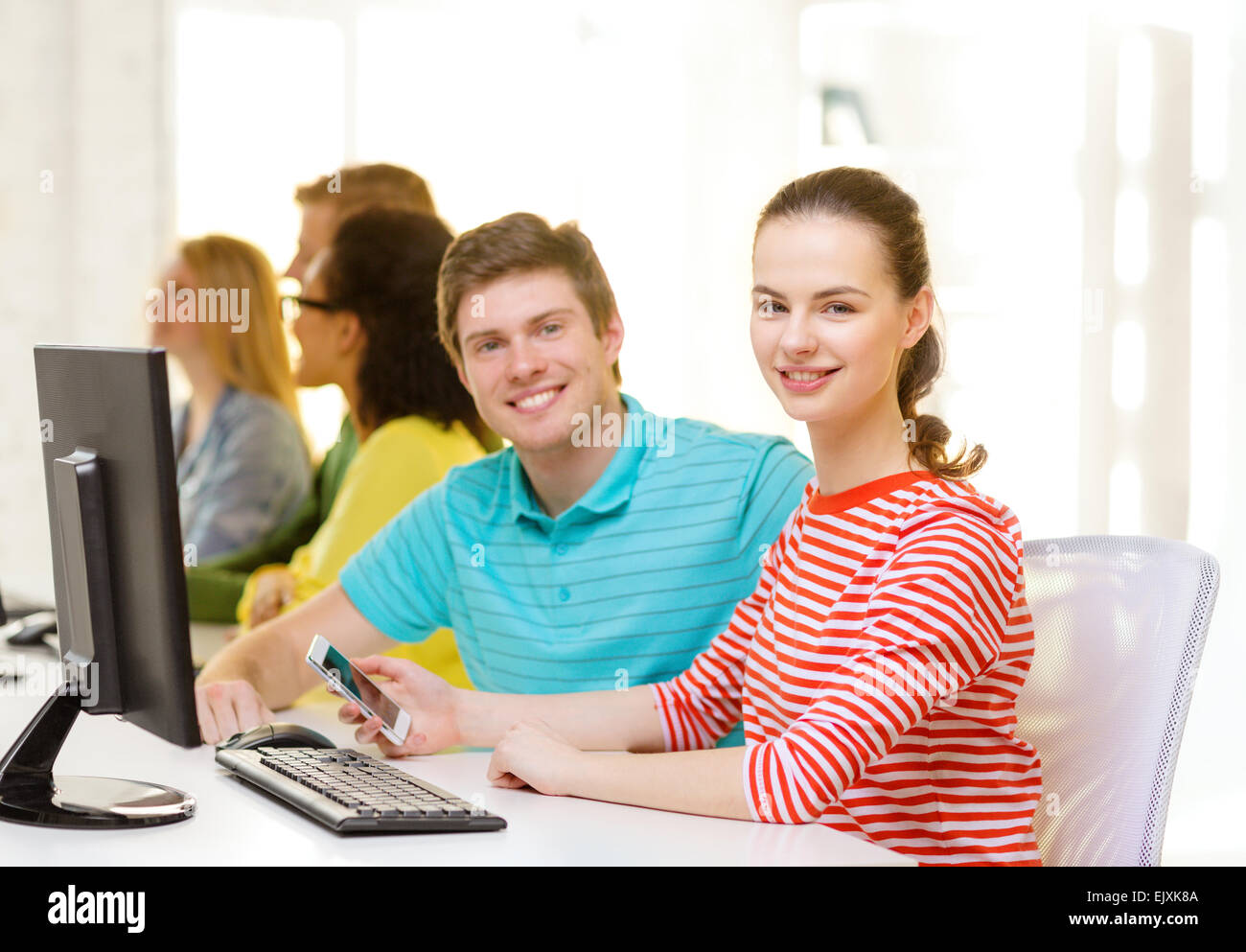 smiling student with smartphone in computer class Stock Photo - Alamy