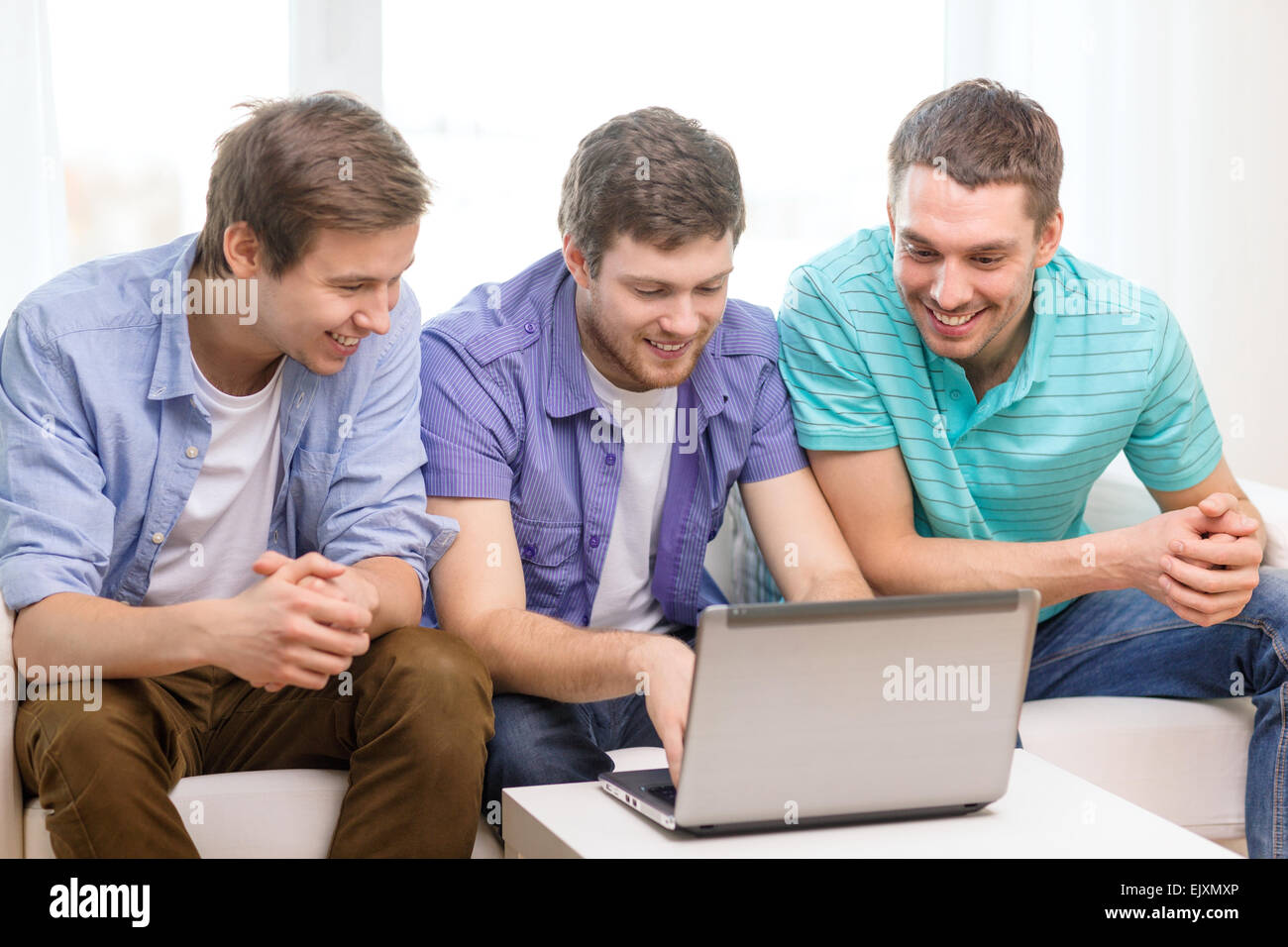 smiling friends with laptop computer at home Stock Photo - Alamy