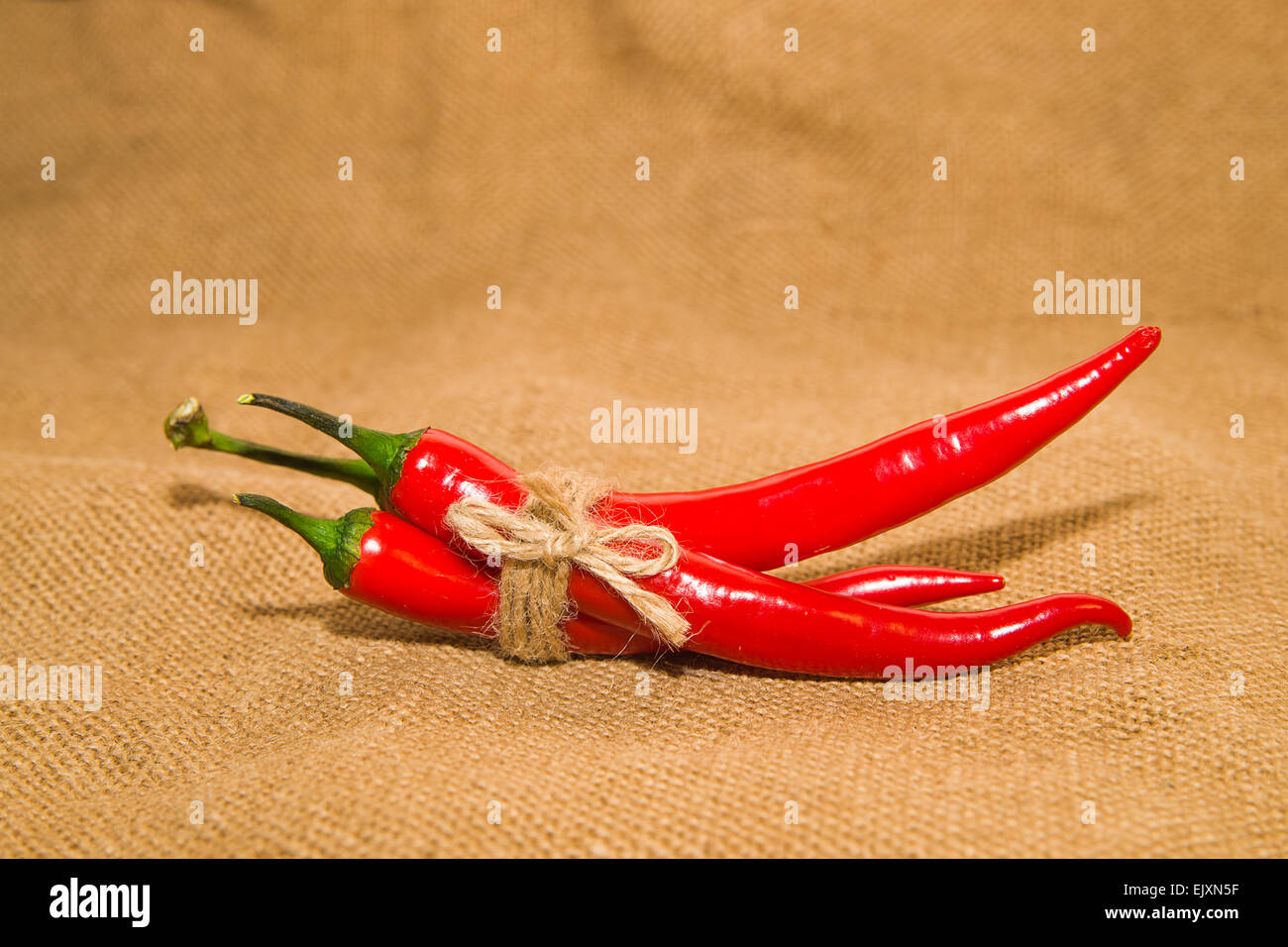 Three Chile peppers tied with a rope on old cloth Stock Photo - Alamy