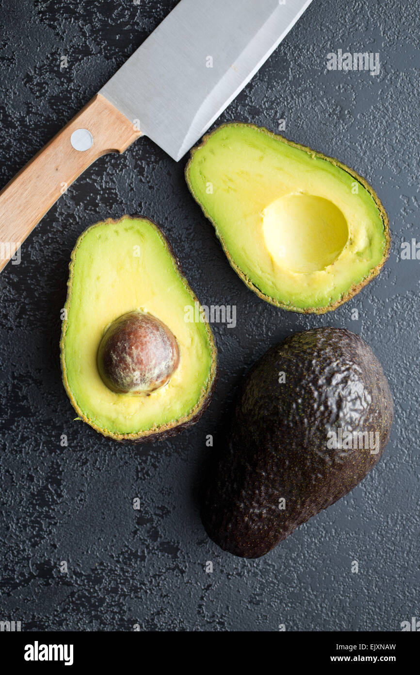 halved avocado on old black table Stock Photo - Alamy