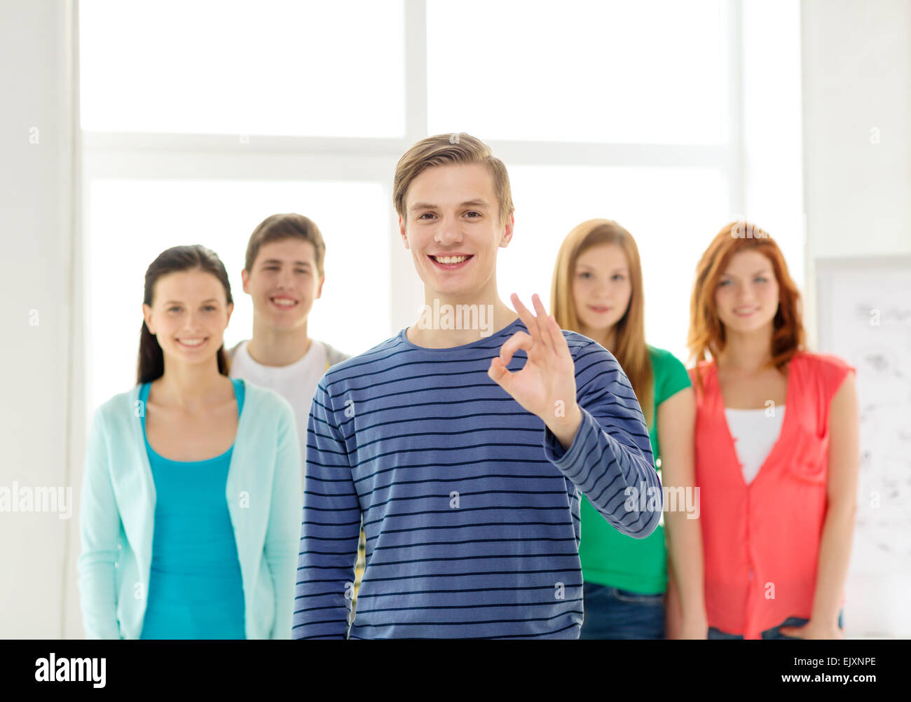 students with teenager in front showing ok sign Stock Photo - Alamy