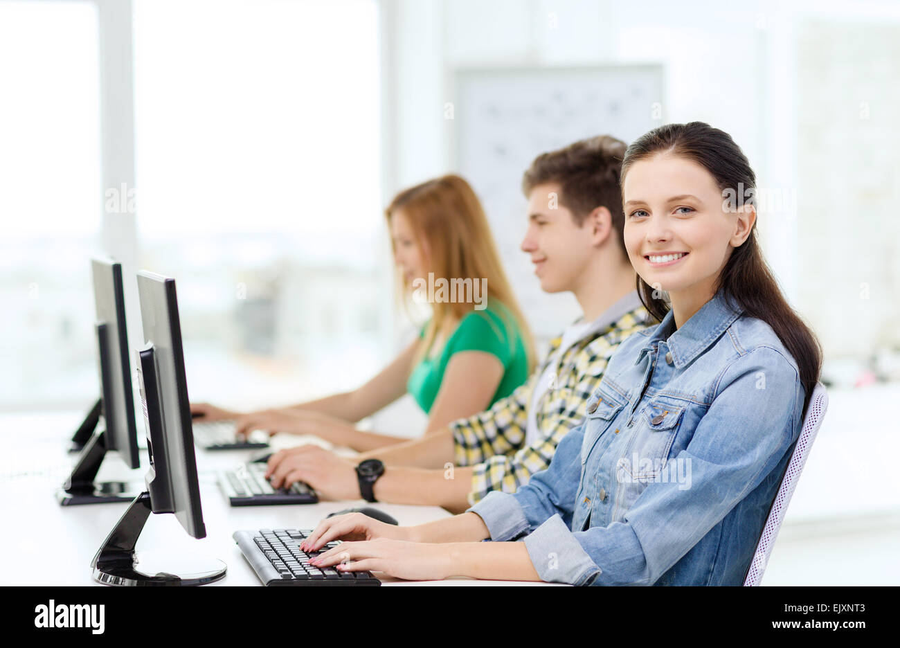 three smiling students in computer class Stock Photo - Alamy