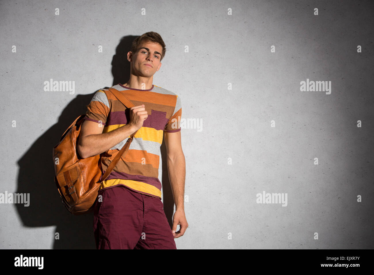 Man with a leather backpack leaning against the wall Stock Photo - Alamy