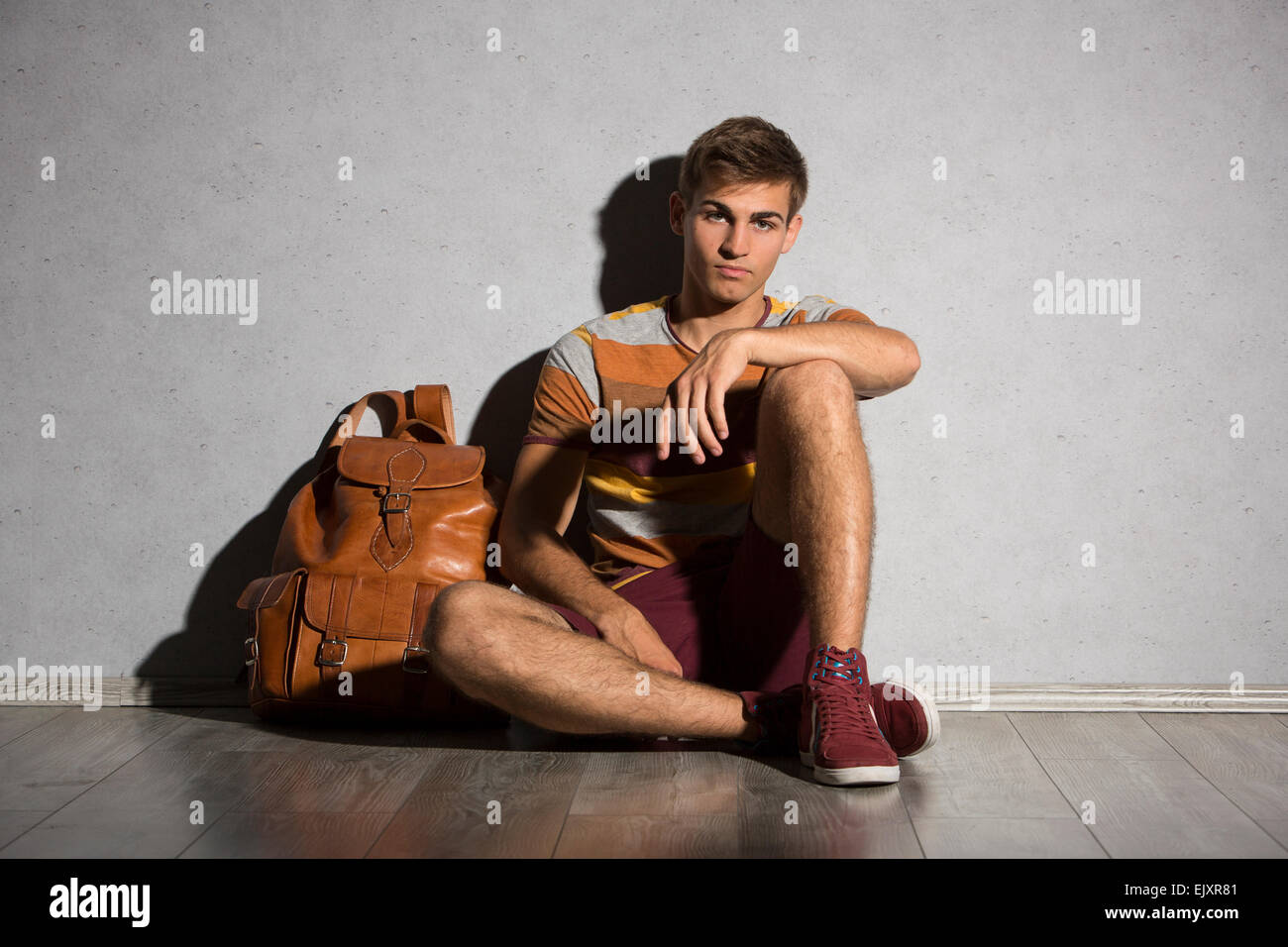 Man with a leather backpack sitting on floor Stock Photo - Alamy