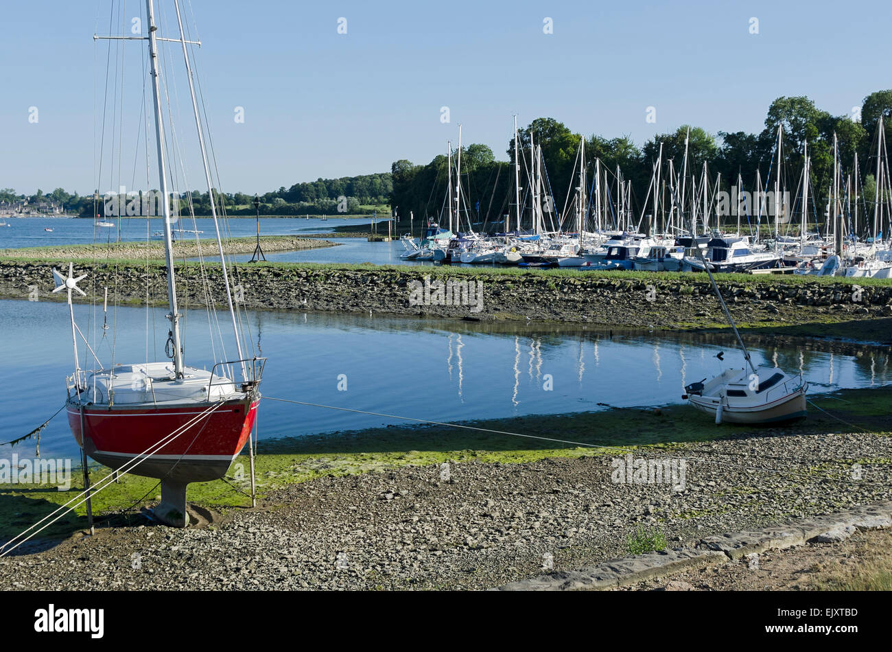 Plouer sur Rance marina at low tide with yacht aground on river bank ...