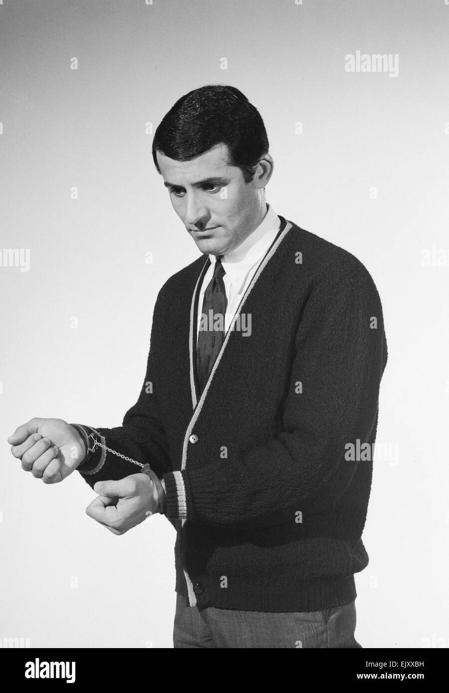 Handcuffs feature. Model Henry Fern in cardigan wearing handcuffs Stock ...