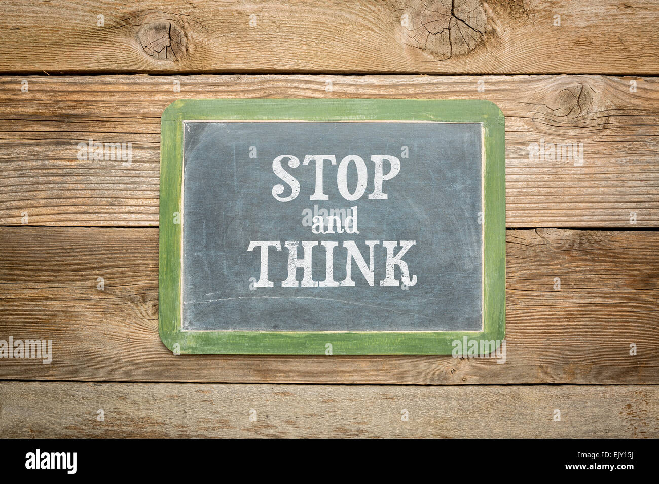 stop and think text on a slate blackboard against rustic weathered wood ...