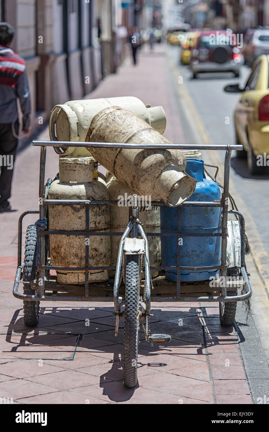A tricycle cart carrying multiple large gas canisters on a busy urban ...