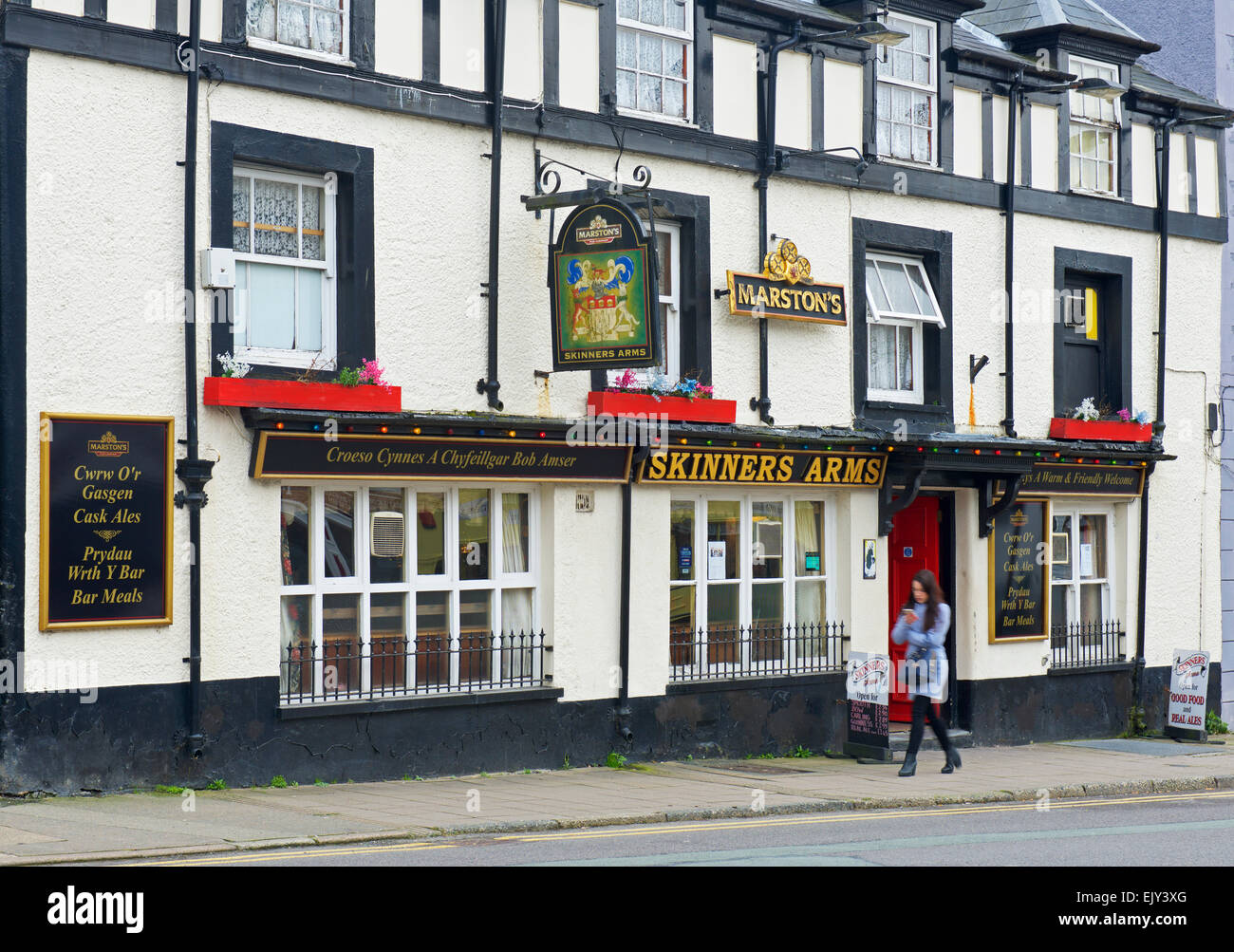 Girl walking past the Skinners arms pub in Machynlleth, Powys, North ...