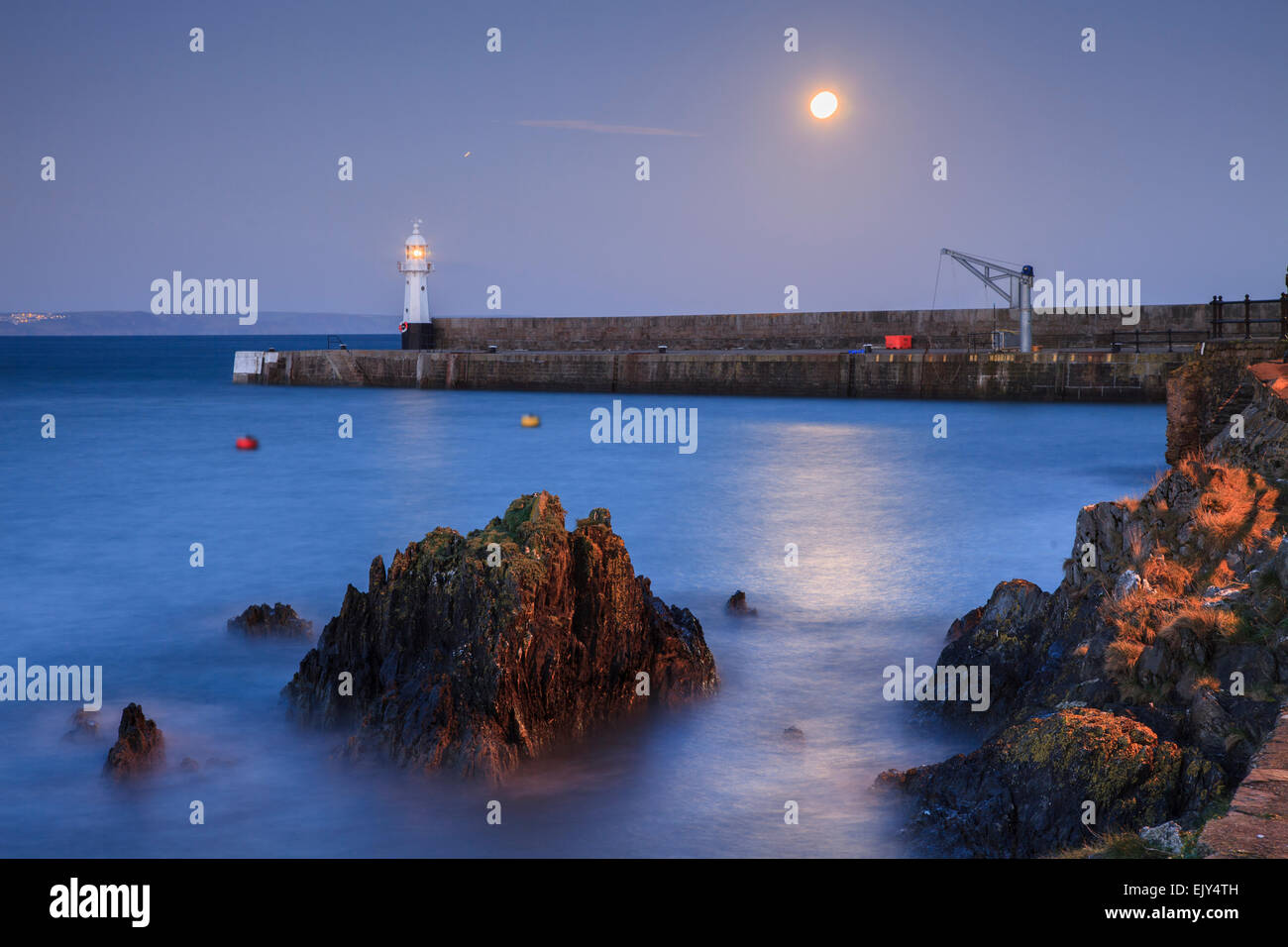 The Moon reflected in the outer harbour at Mevagissey in Cornwall, with ...