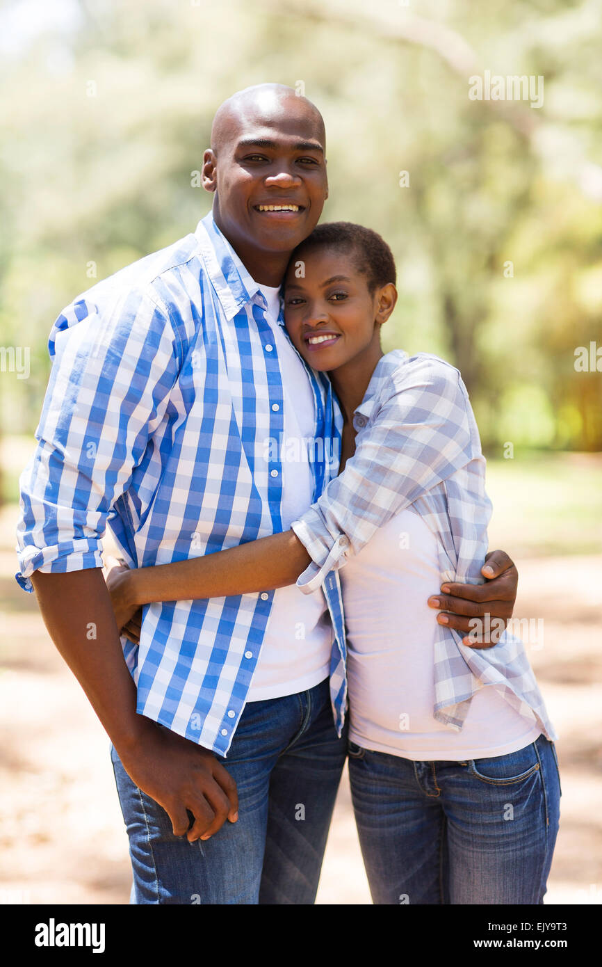 portrait of young African American couple hugging outdoors in forest ...