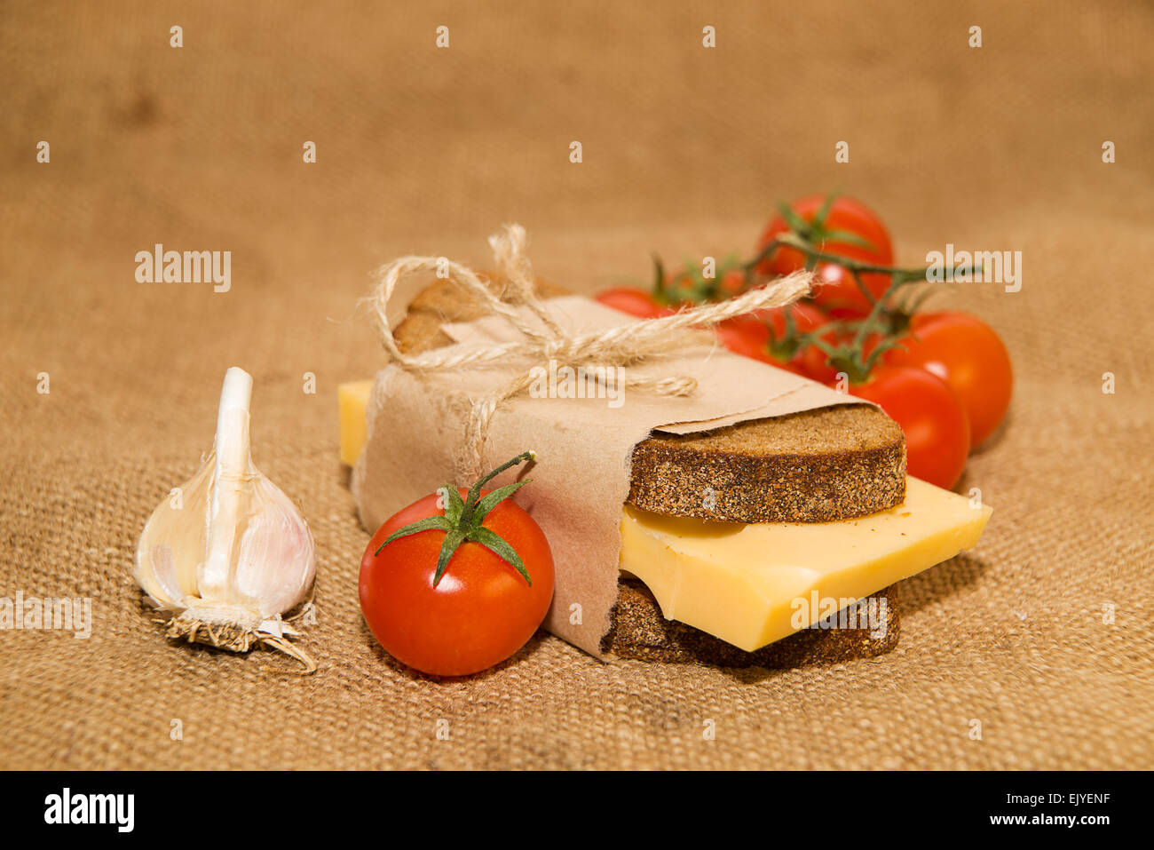 Sandwich with cheese wrapped in paper, cherry tomatoes and garlic on ...