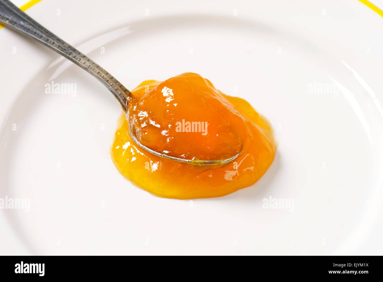 Spoon of apricot jam on plate Stock Photo - Alamy