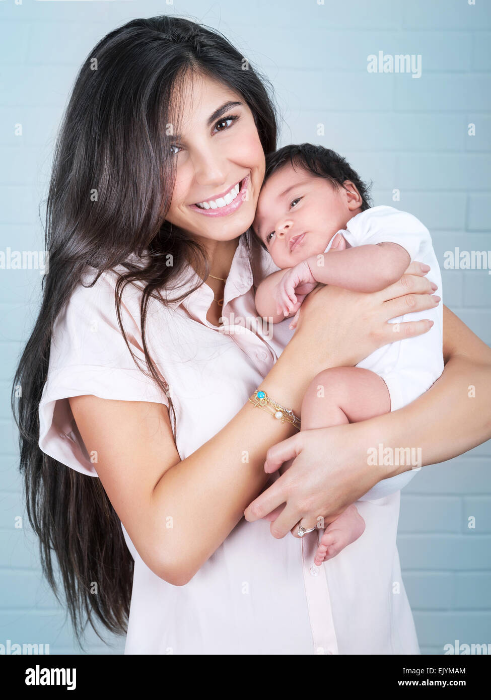Portrait of beautiful cheerful mother with cute little baby on hands ...