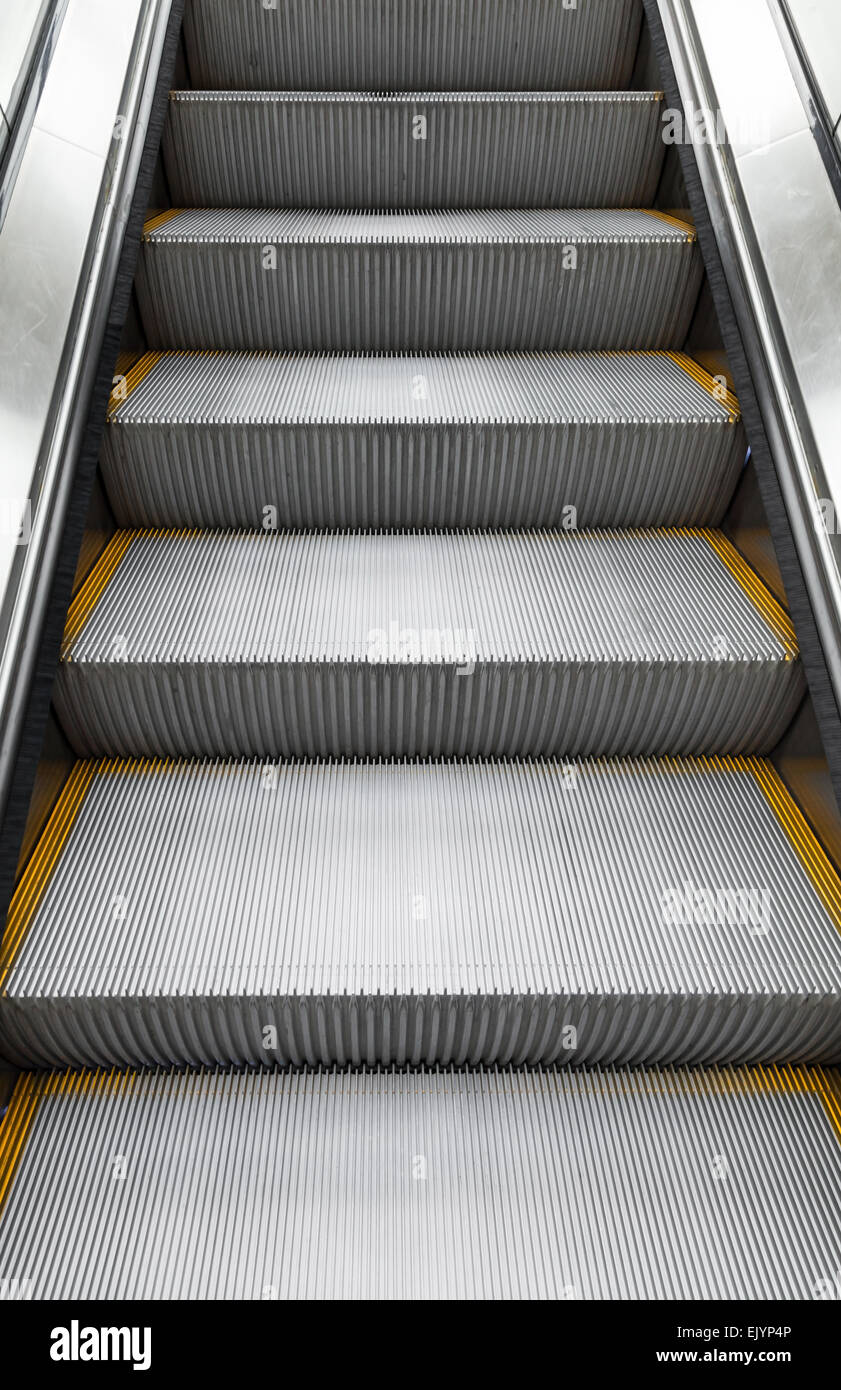 Shining metal escalator moving up, vertical photo with perspective ...