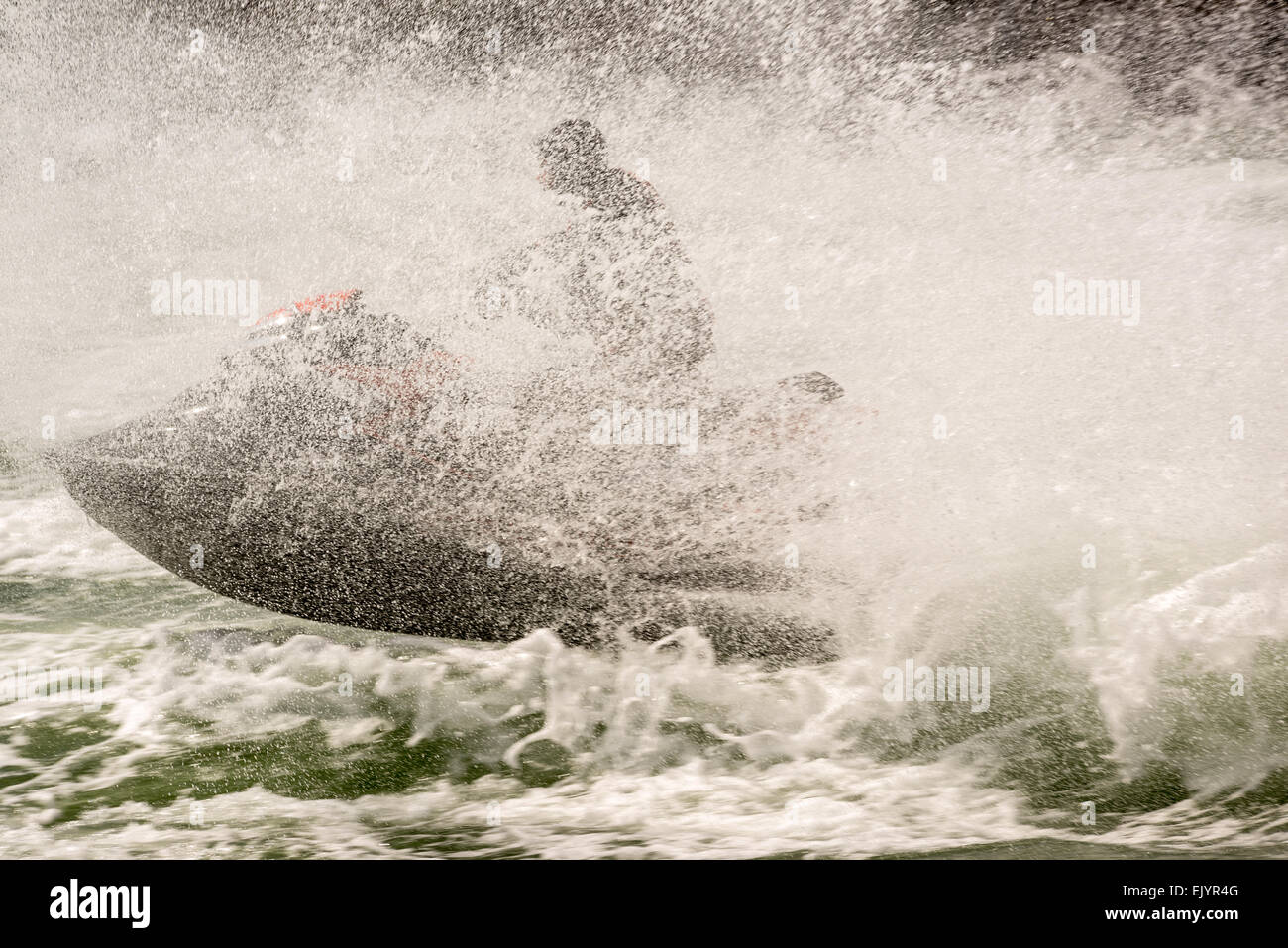 Jet ski through spray and wake, rider and jet ski obscured by the spray ...