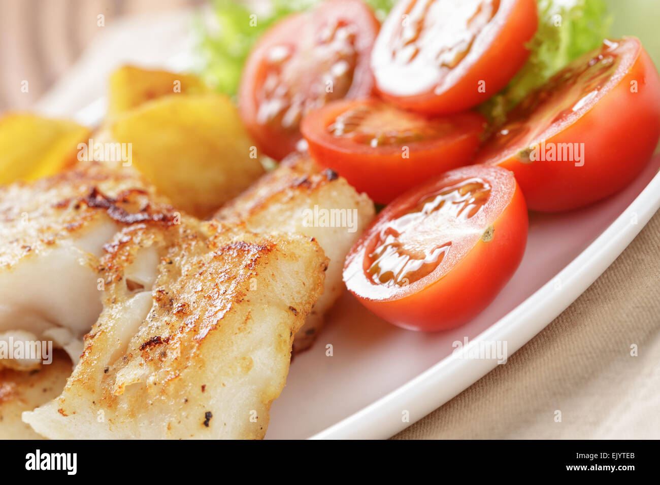 fried fish fillet with vegetables on wood table Stock Photo - Alamy
