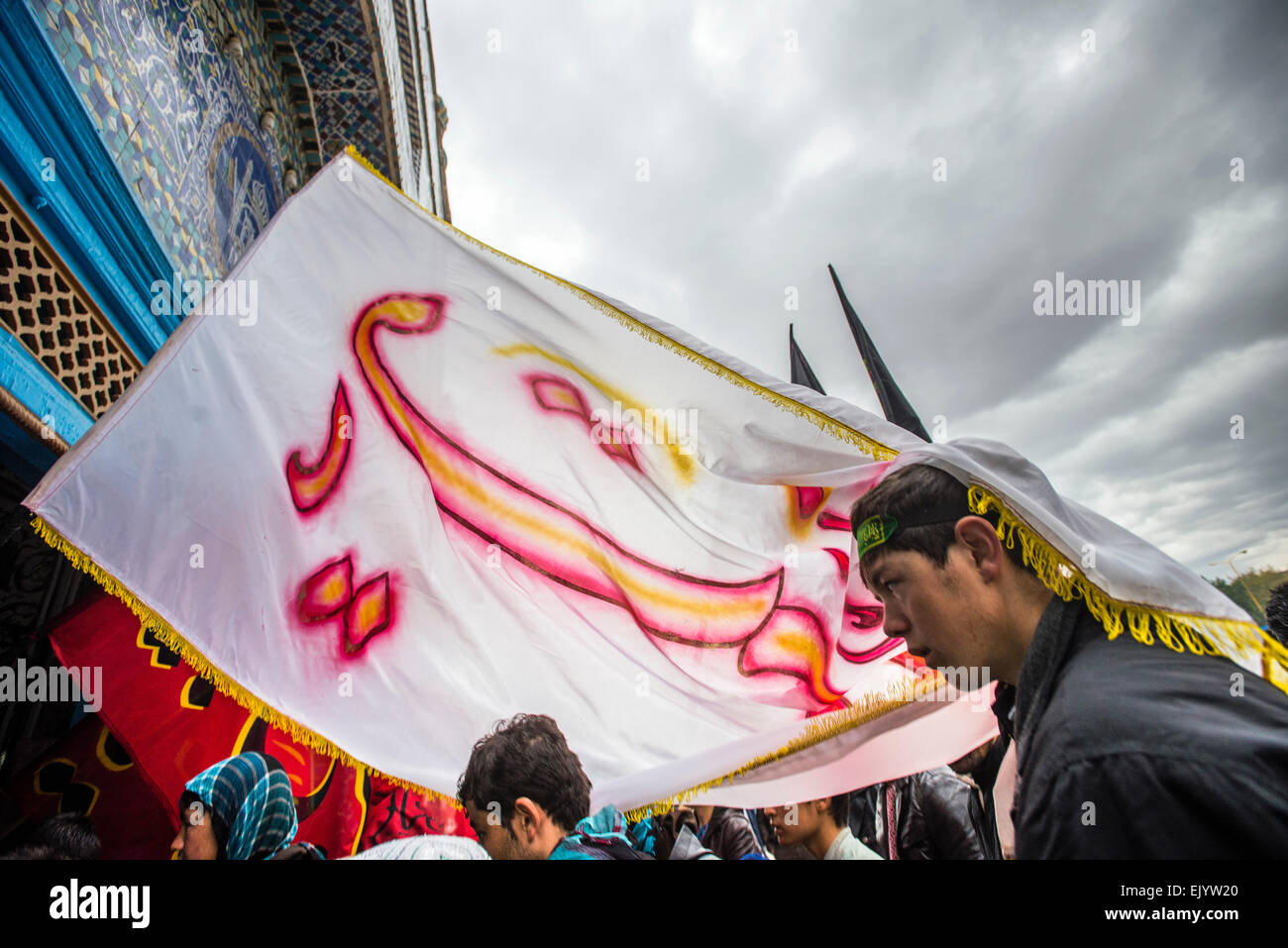 People carry festive flag in the yard of Shrine of Ali on Day of Ashura ...