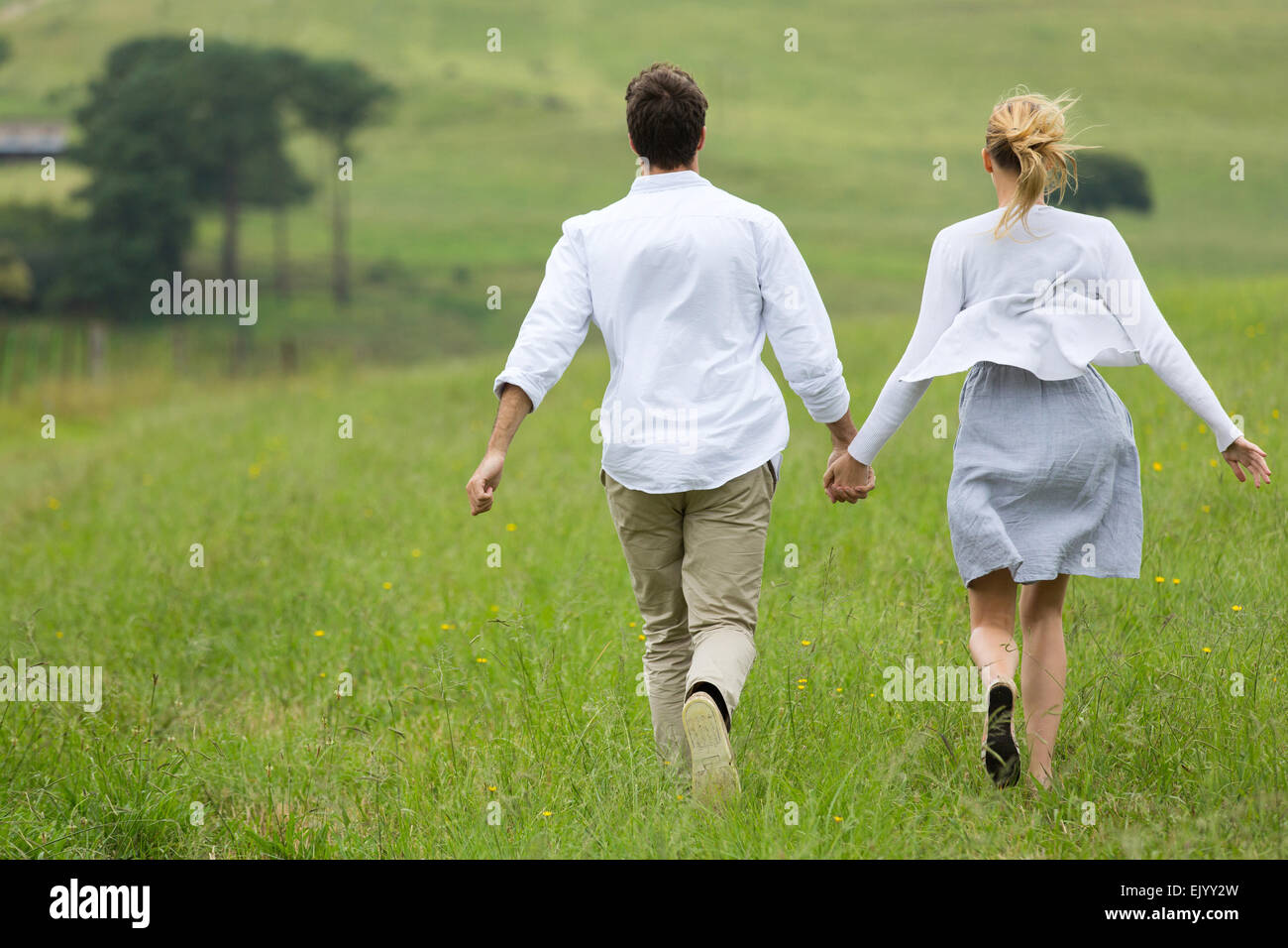 lovely couple running together on a green field Stock Photo - Alamy