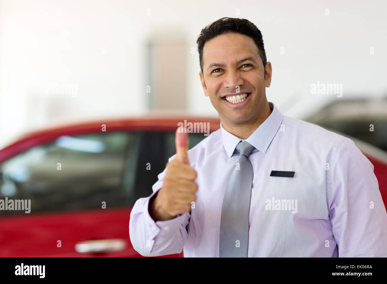 handsome car salesman thumb up at car dealership Stock Photo - Alamy