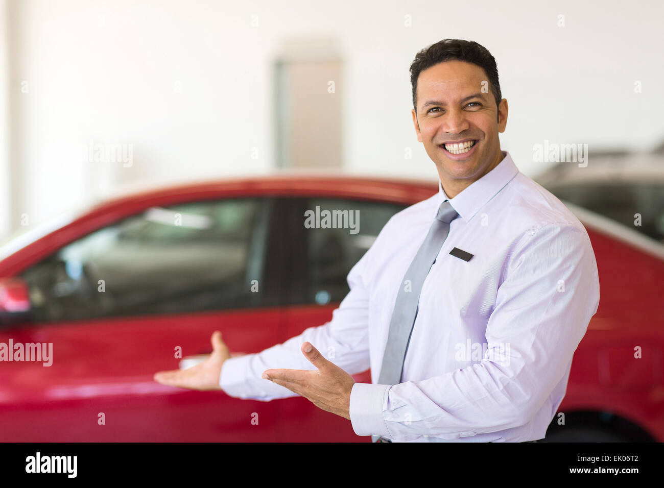 handsome vehicle salesman presenting new cars in showroom Stock Photo ...
