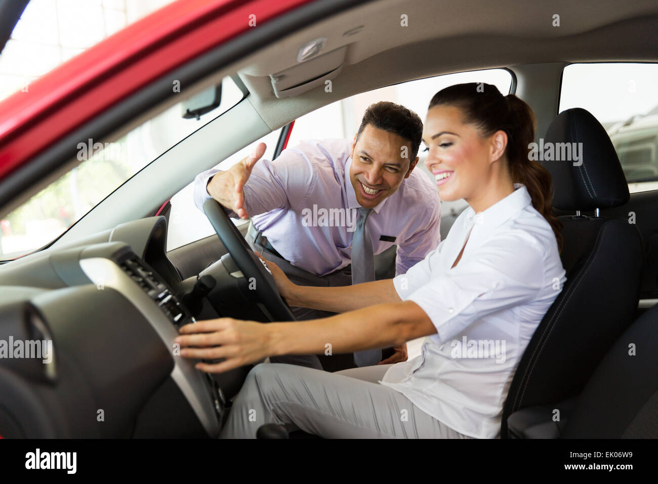 friendly car sales consultant showing a new car to young woman Stock ...