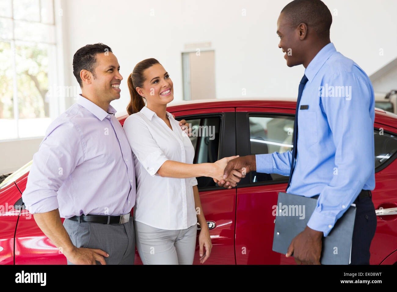 beautiful couple handshake with car salesman after purchasing a car ...