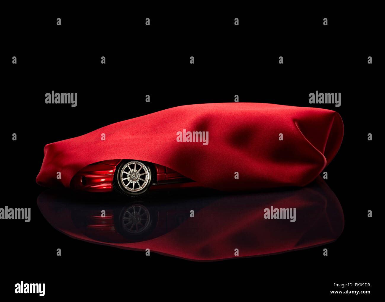 close up of a new car hidden under red cover on black background with ...