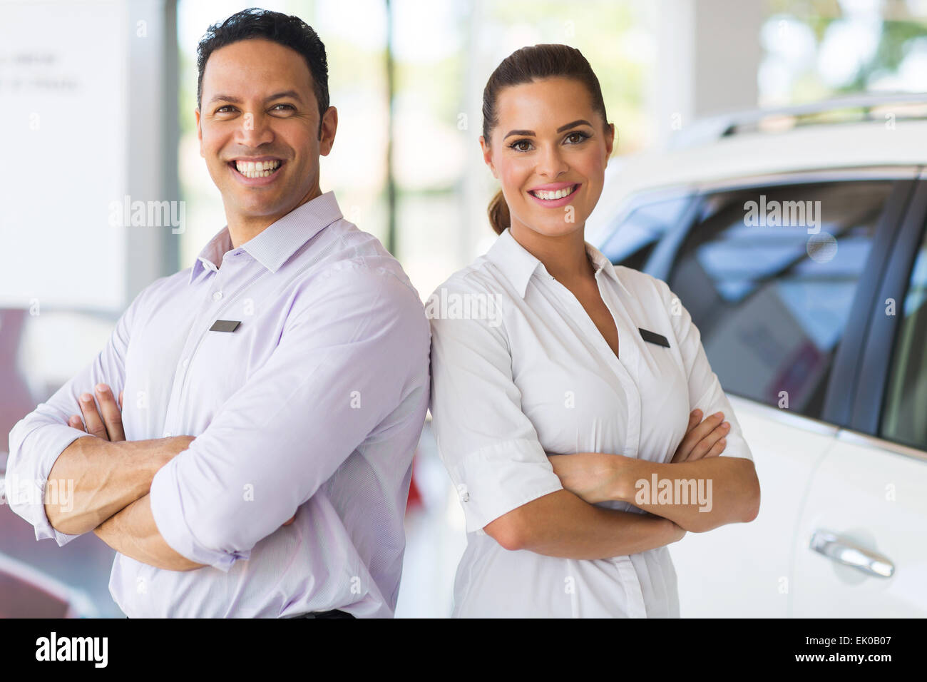 portrait of happy sales staff standing in vehicle showroom Stock Photo ...
