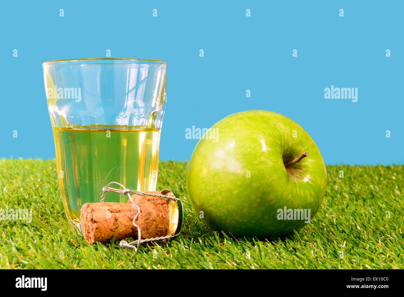 a green apple with a glass of cider on grass Stock Photo - Alamy