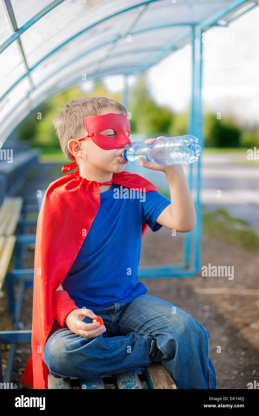 Boy dressed in cape and mask drinking water from a bottle Stock Photo ...