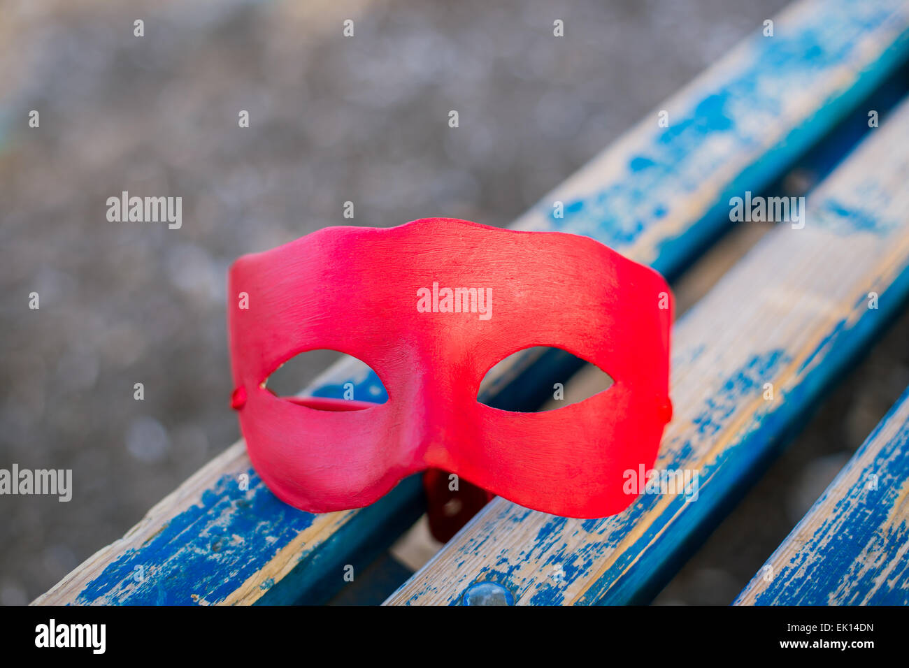 Painted red mask lying on blue old bench Stock Photo - Alamy