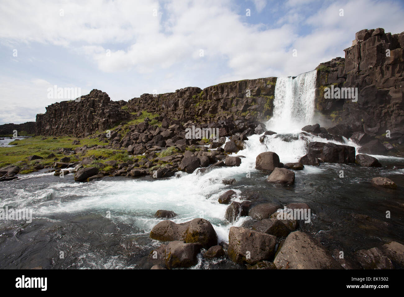 Waterfall flows over a cliff of lava rock formations in Thingvellir ...
