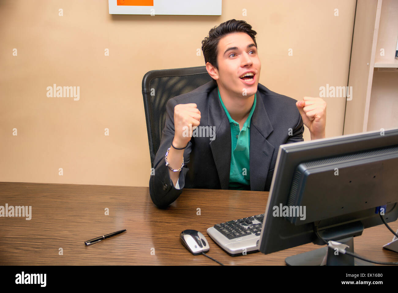 Happy young businessman screaming for joy, sitting at desk in his ...