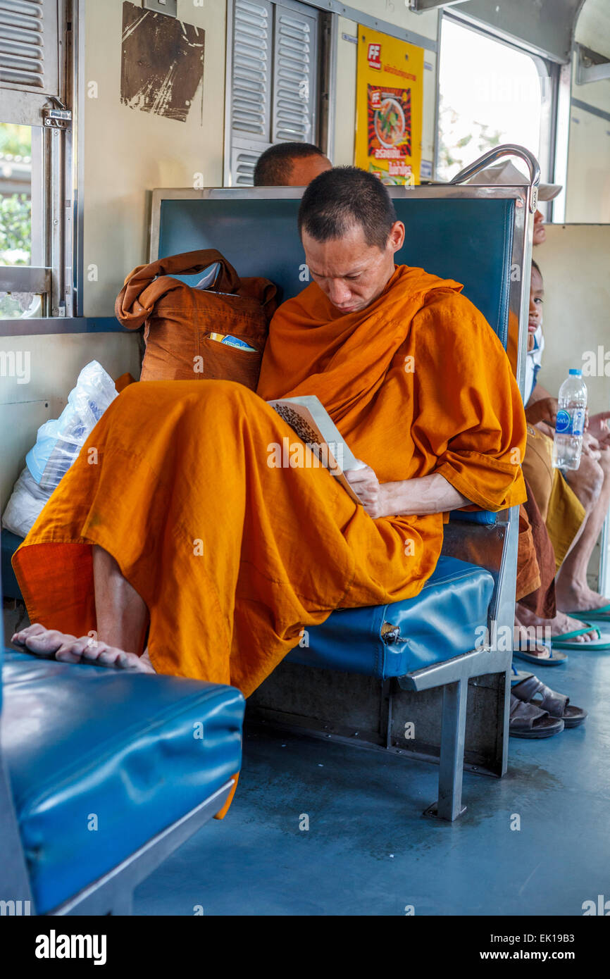 A young monk reading a book on a train, Thailand Stock Photo - Alamy