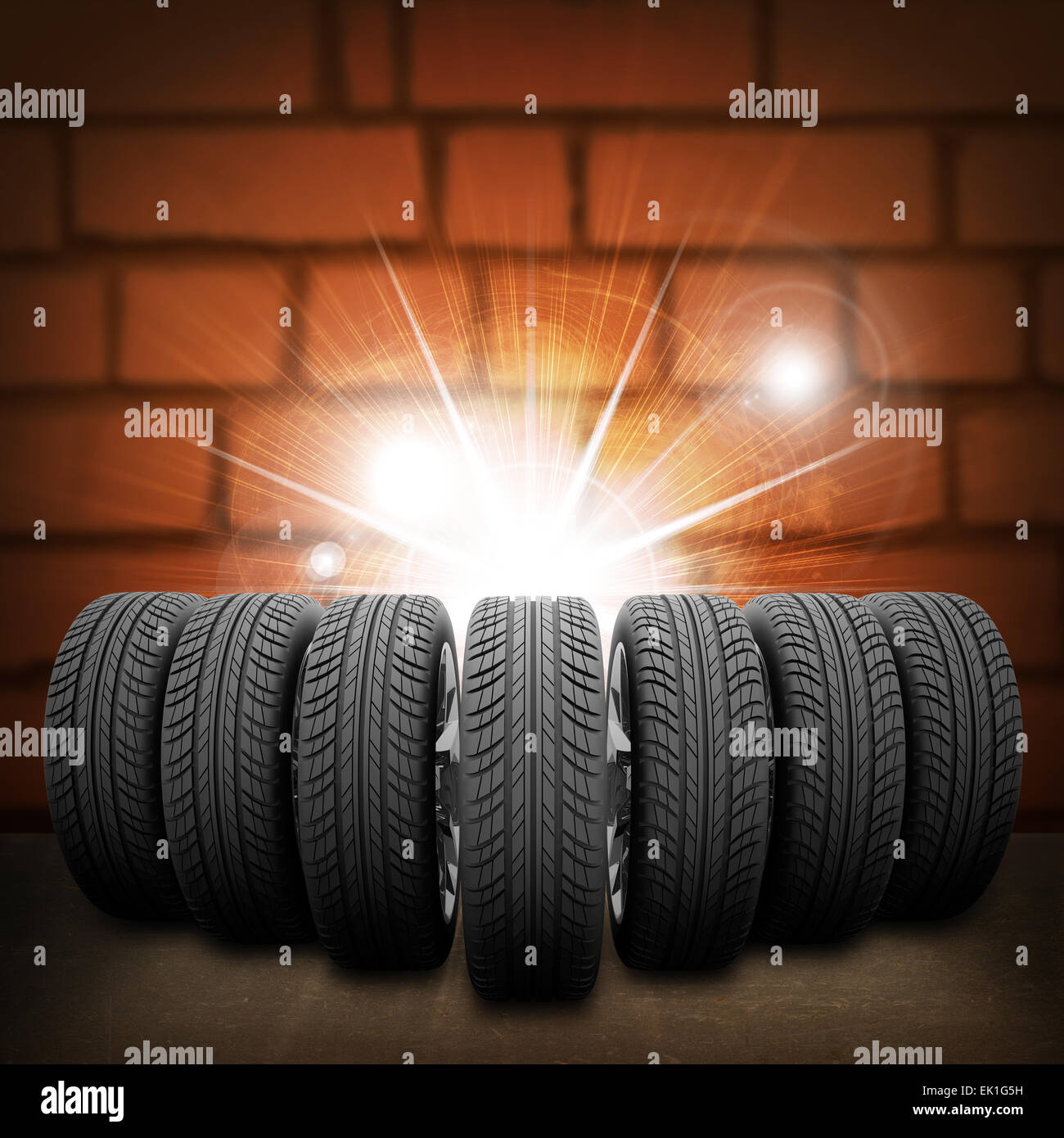 Wedge of new car wheels. Red brick wall, concrete floor and light at ...
