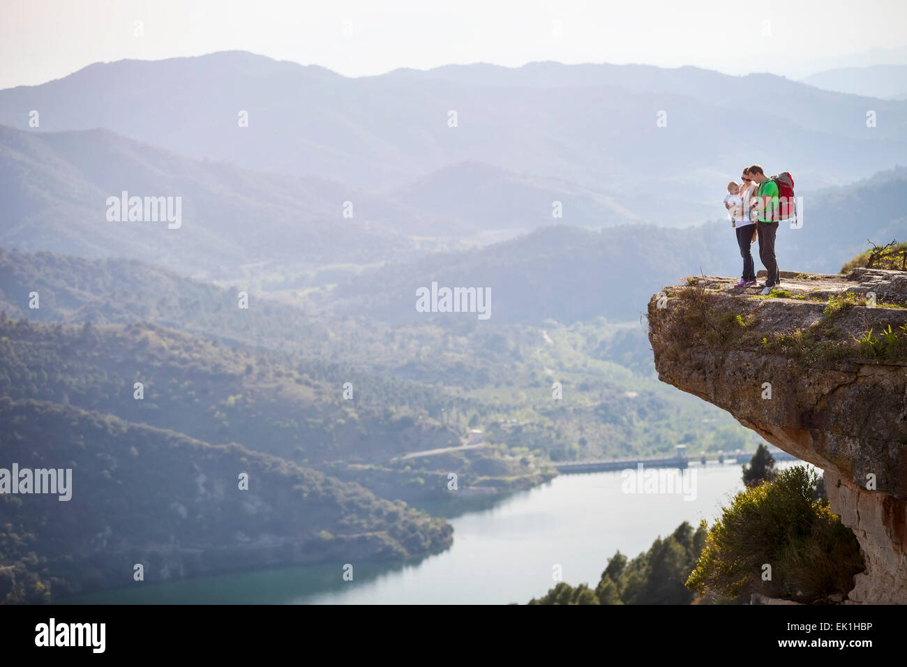 Happy young couple with little son standing on cliff over river Stock ...