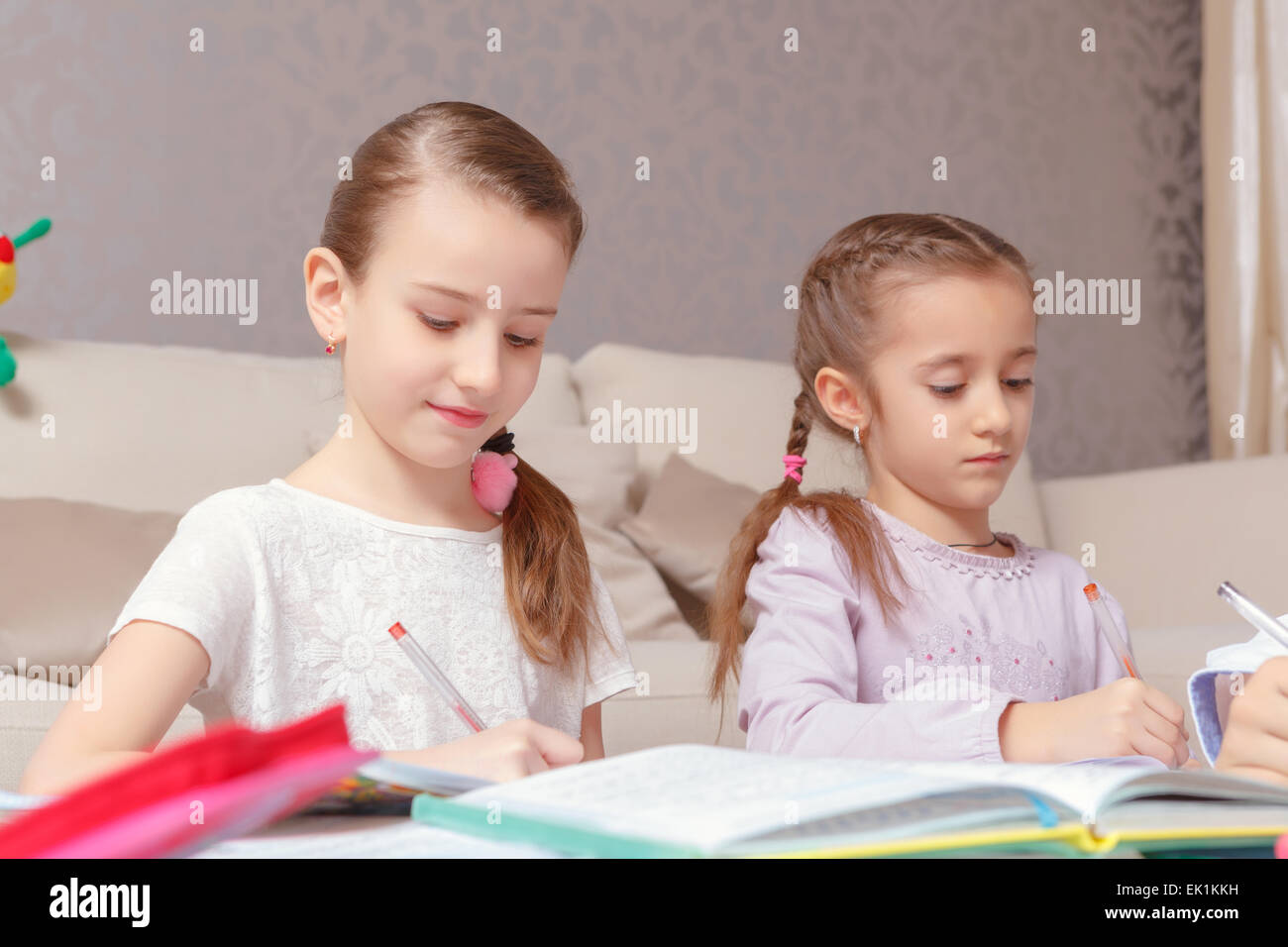Two girls write in their exercise books Stock Photo - Alamy