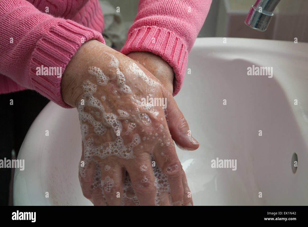 Close up Elderly woman washing hands in bathroom washbasin personal ...