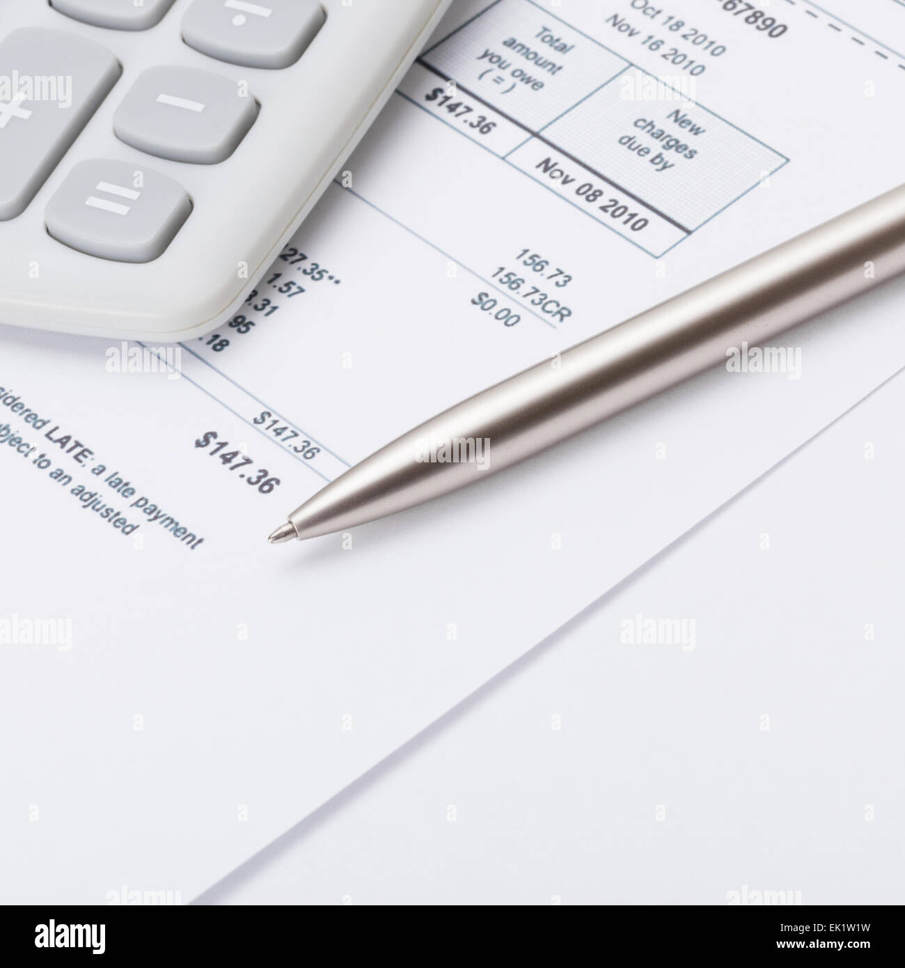 Neat calculator with silver pen and utility bill under it - close up ...