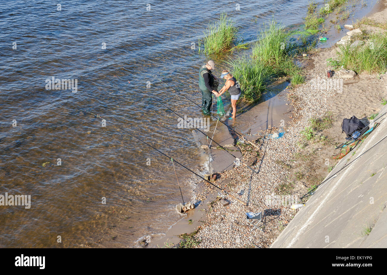 Man and woman fishing on the fishing rod on the bank of the Volga River ...