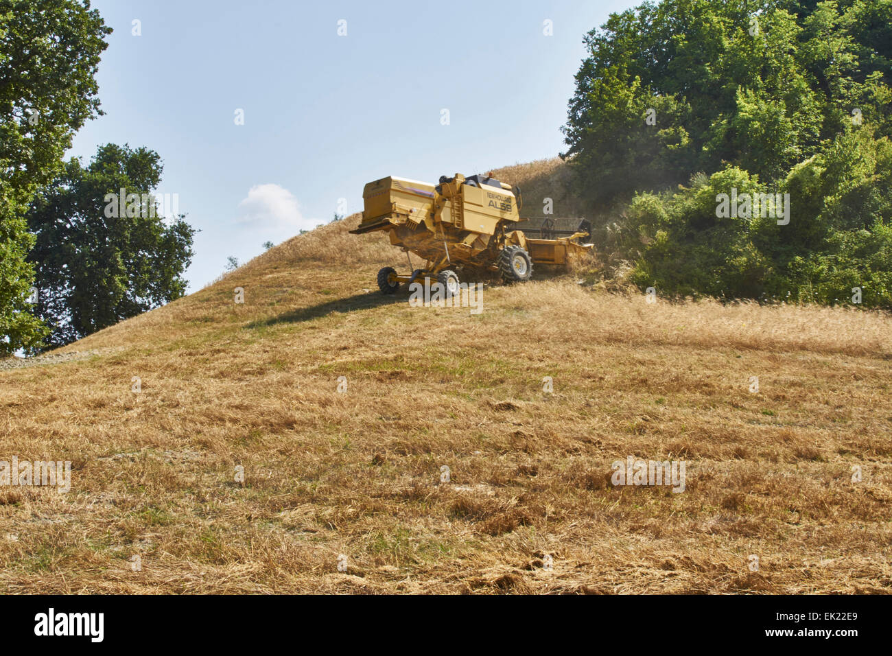 Heavy modern machinery harvesting crop on sides of hilly fields Stock ...