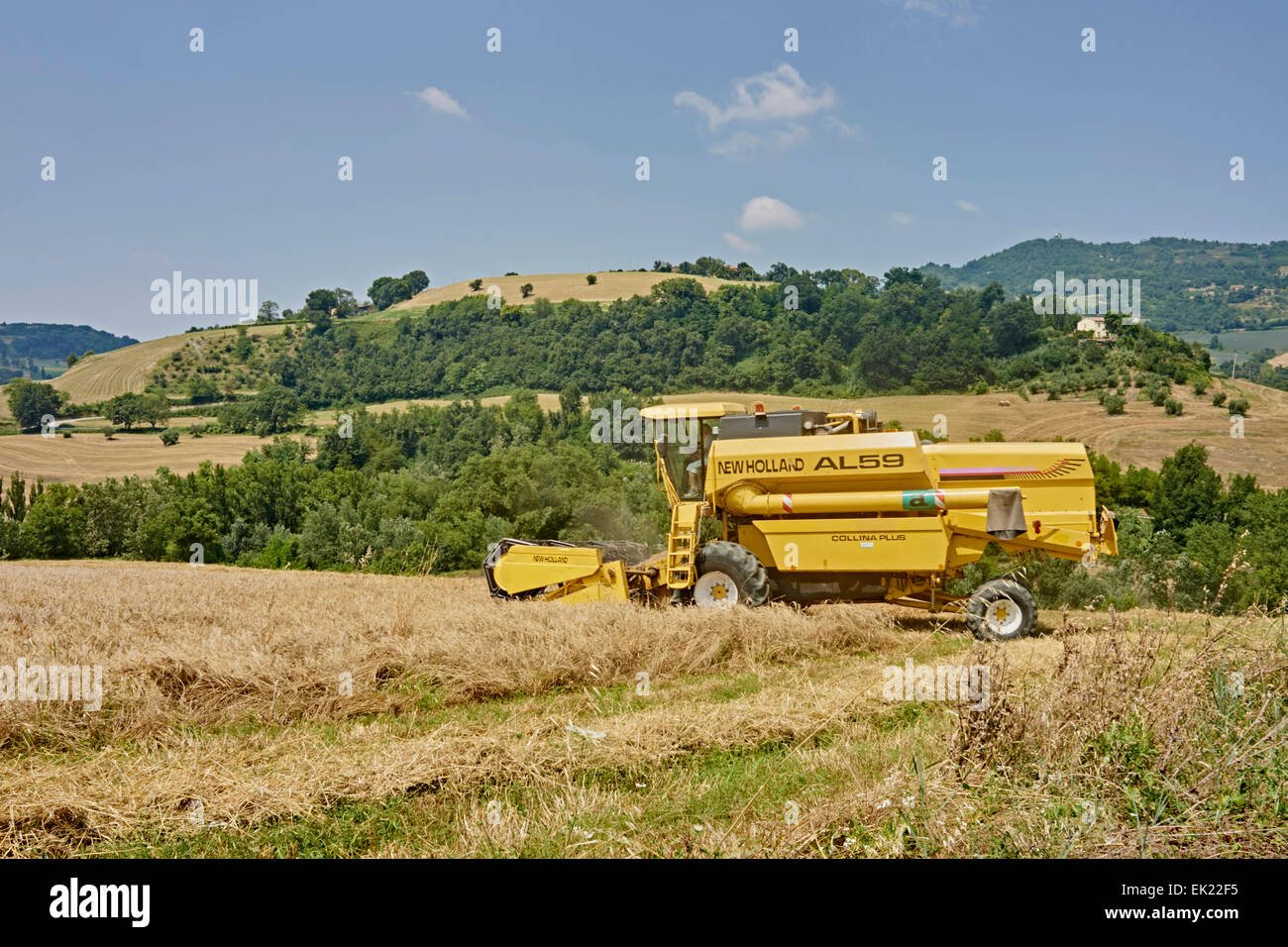 Heavy modern machinery harvesting crop on sides of hilly fields Stock ...