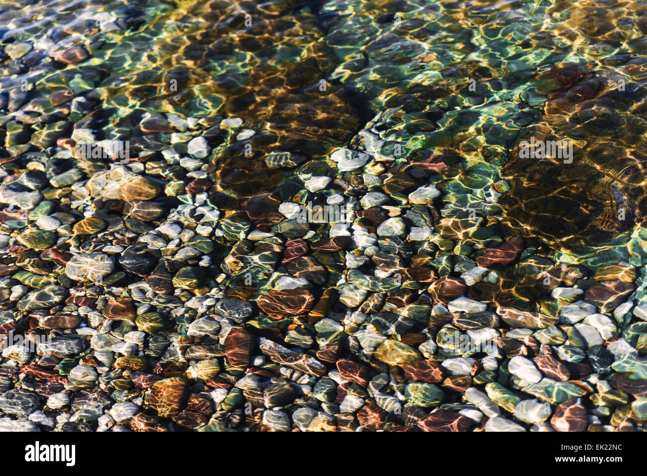 Multi-colored stones in clear water on the beach Stock Photo - Alamy