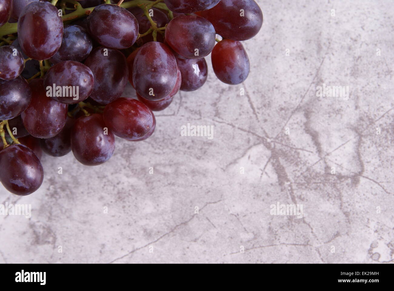 Ripe red grapes laying on a white marble surface waiting to be eaten ...