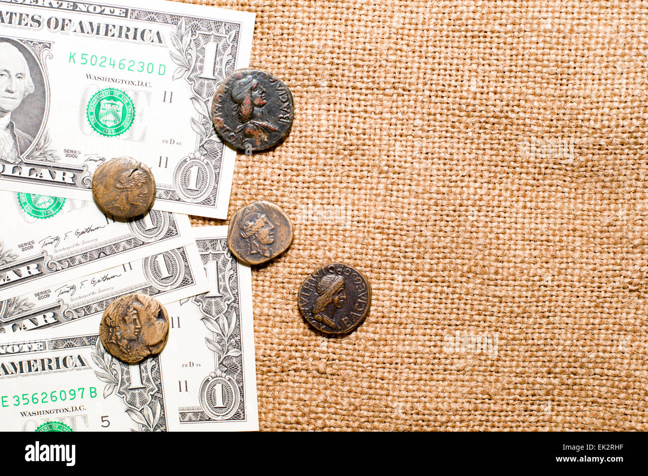 Ancient coins with portraits of emperors and dollar notes on sacking ...